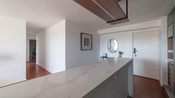 Uma cozinha moderna com bancada de mármore, viga de madeira no teto, um quadro na parede e uma porta que dá para outro cômodo.