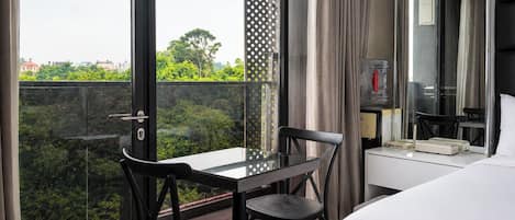 Quarto de hotel com uma varanda grande, uma cama, uma escrivaninha e uma cadeira.