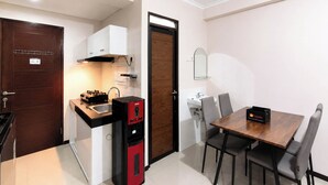 Uma cozinha compacta com fogão, pia e uma mesa de jantar com cadeiras.