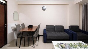 Um espaço de estar compacto com uma mesa de jantar, dois sofás, uma mesa de centro, um relógio de parede e um espelho.