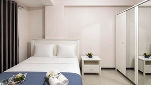 Quarto de hotel com uma cama, mesas de cabeceira, um espelho e um guarda-roupa.