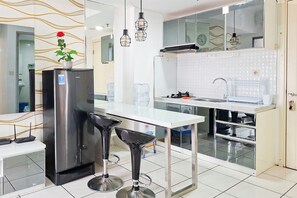 Uma cozinha moderna com geladeira, banquetas de bar, pia e uma rosa decorativa.