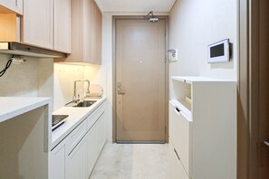 Uma cozinha estreita com pia, armários e uma porta que dá para outro cômodo.