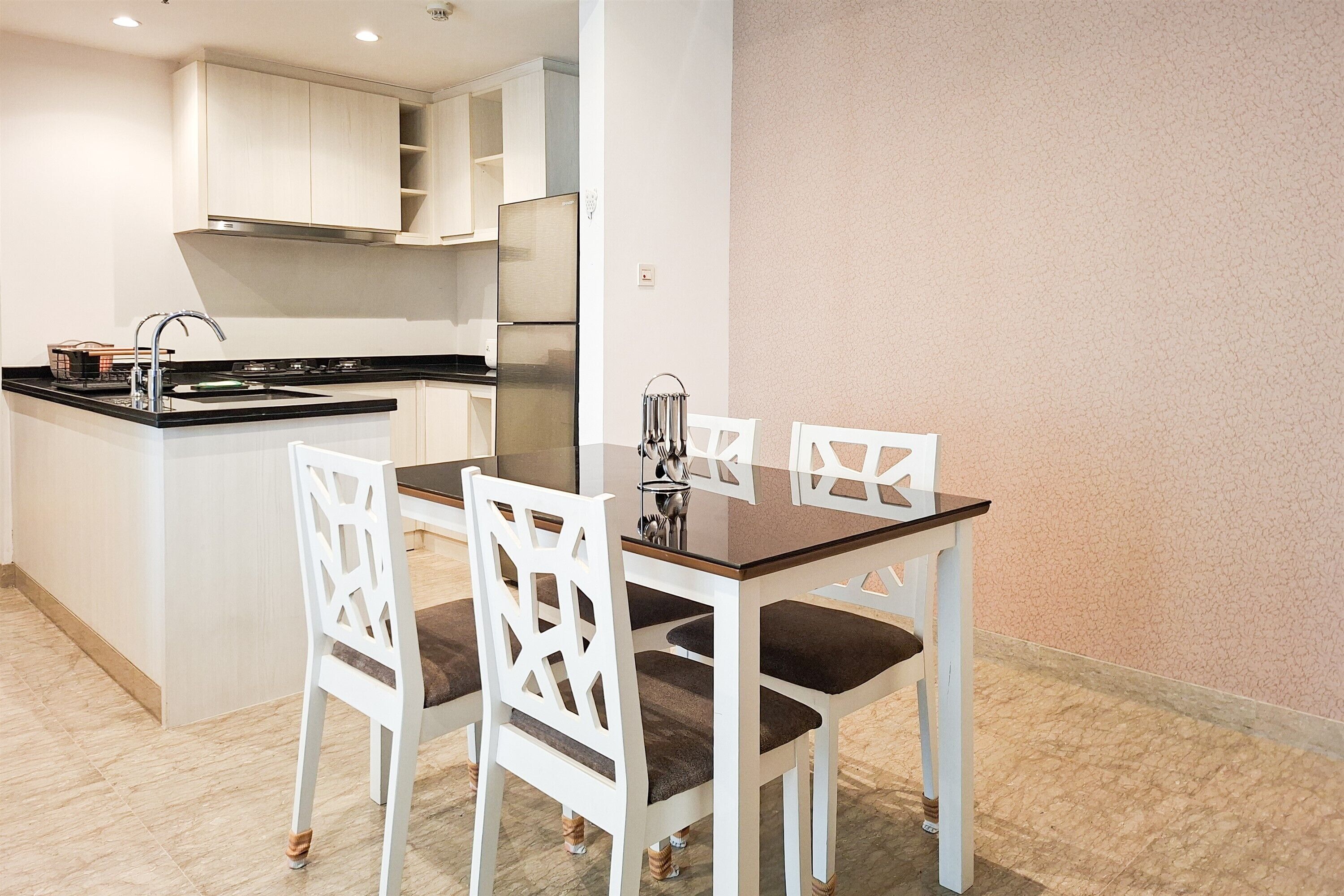Uma cozinha compacta com mesa e cadeiras, forno embutido e geladeira.