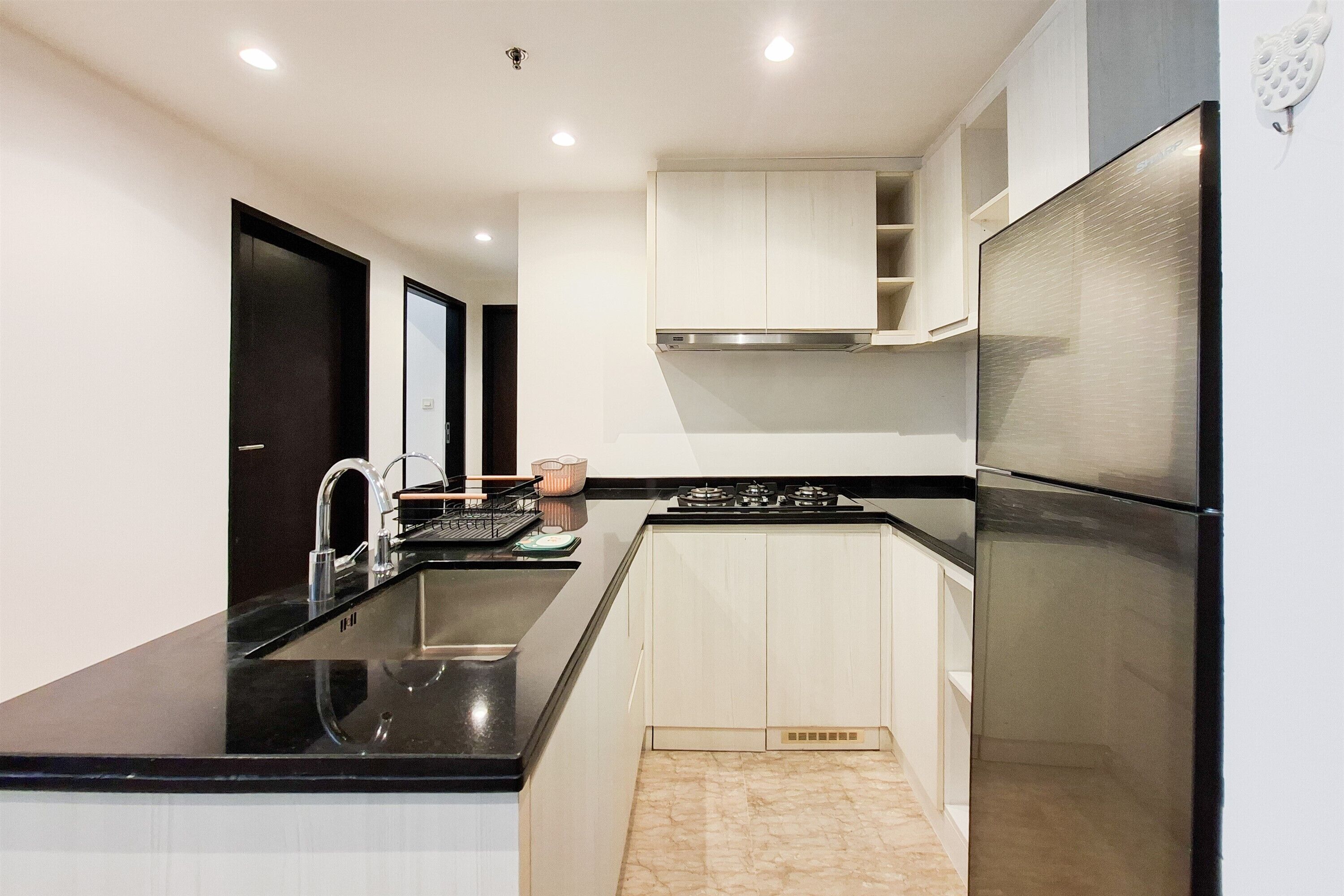 Uma cozinha moderna com bancada preta, eletrodomésticos de aço inoxidável e armários brancos.