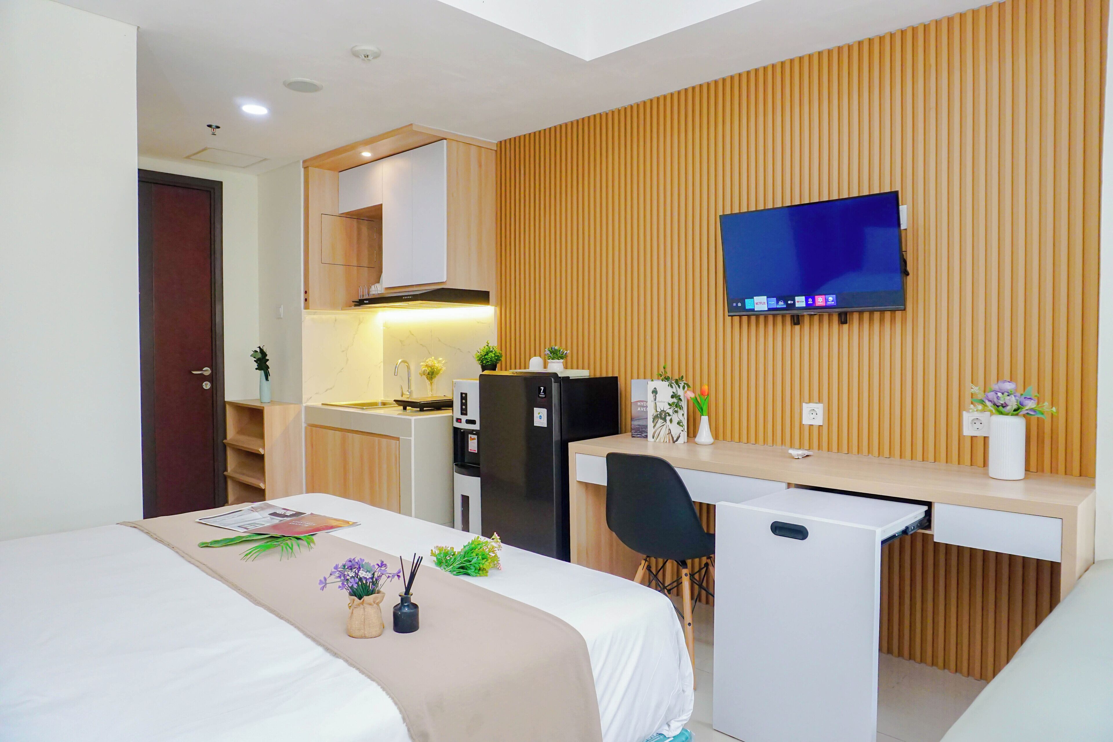Quarto de hotel com uma cama, uma escrivaninha, uma televisão, um mini-frigobar, micro-ondas e uma pequena cozinha.