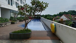 Uma piscina no terraço com um deck de madeira, uma pequena árvore e um flutuador amarelo.
