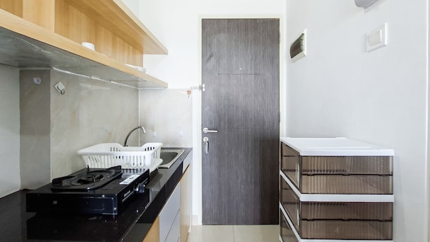 A compact kitchen with a gas stove, a sink, and a door leading to another room.