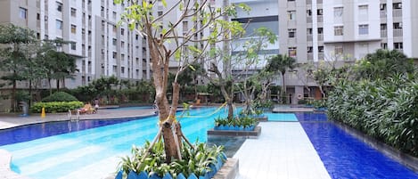 Uma área de piscina com várias pistas de natação, rodeada por árvores e plantas.