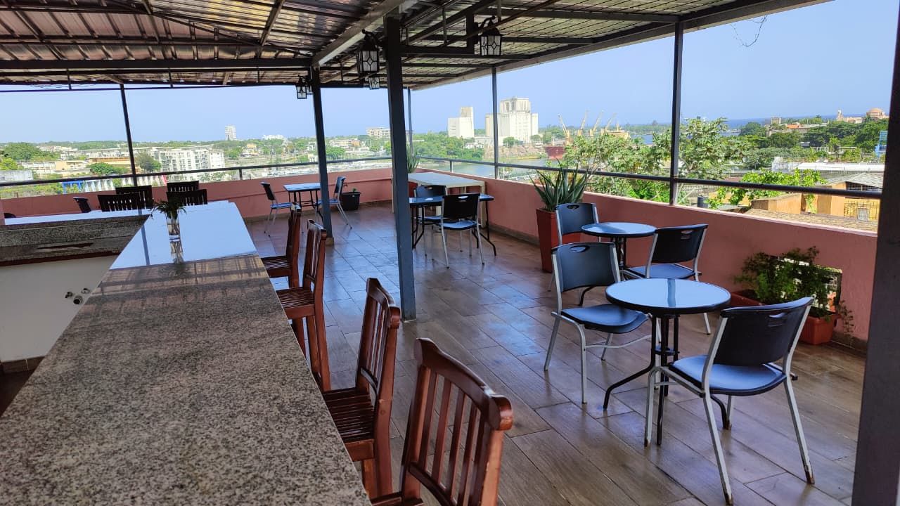 Terraço no telhado com área de bar, assentos e vista para a paisagem urbana.