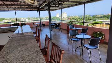 Terraço no telhado com área de bar, assentos e vista para a paisagem urbana.