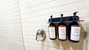 Uma casa de banho com uma prateleira na parede, exibindo três produtos HG Hotel Gallery Cartagena: champô, condicionador e gel de banho.