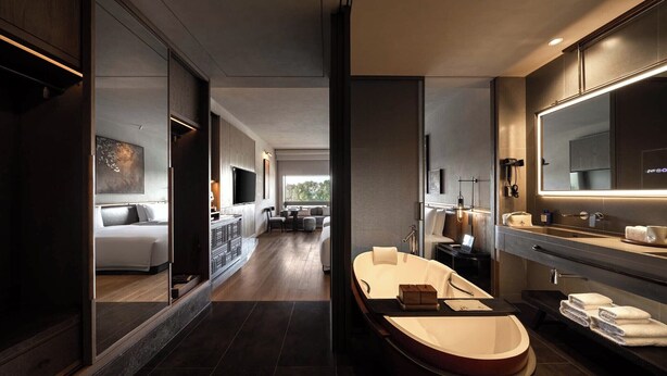 Uma casa de banho de hotel moderna, com um espelho grande, uma banheira e um lavatório elegante.