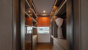 Um closet estreito com portas que permitem a passagem, painéis de madeira, uma janela no final e um roupão pendurado à direita.