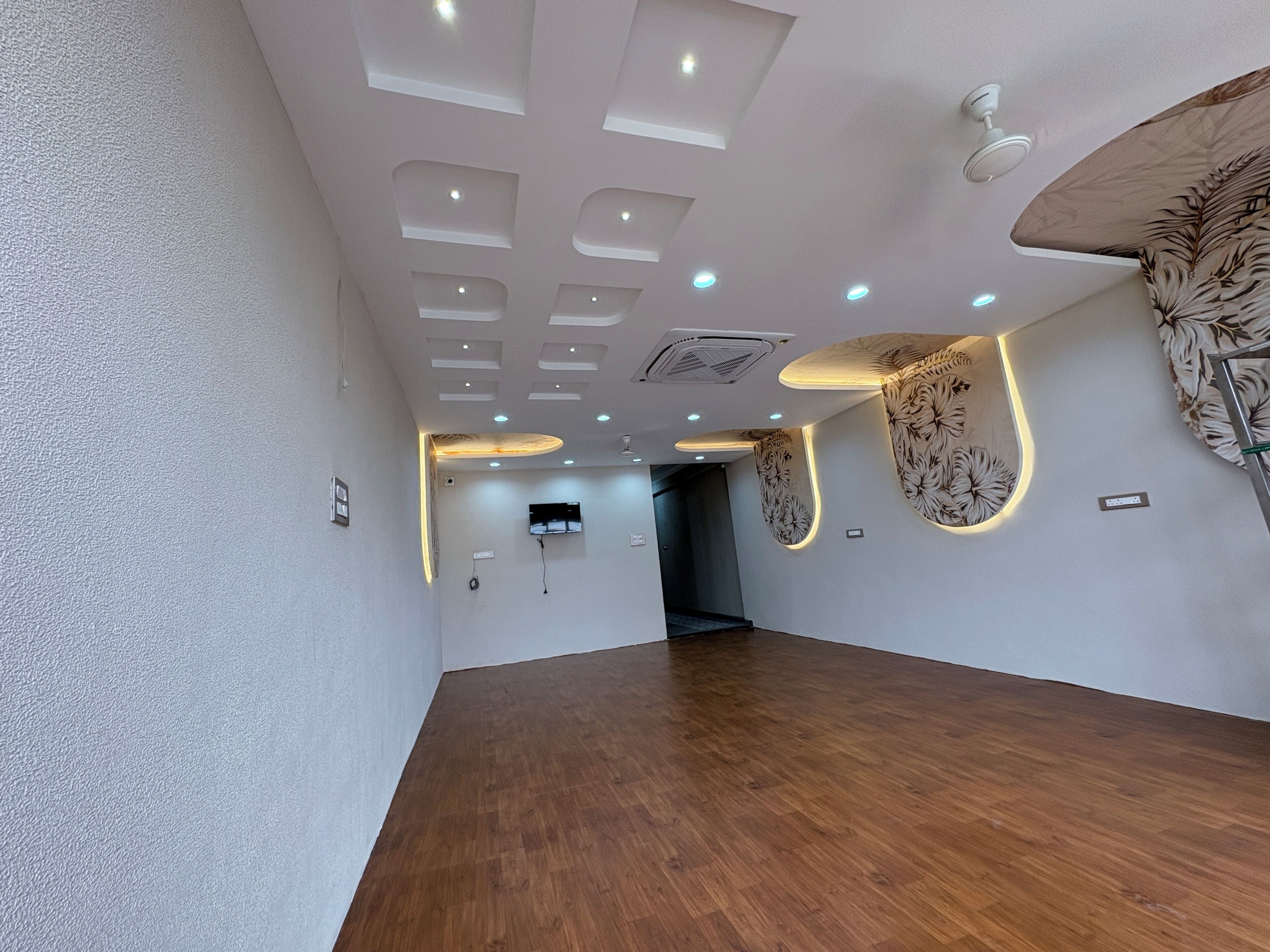 Interior de um hotel moderno com piso de madeira, iluminação embutida e painéis decorativos na parede.