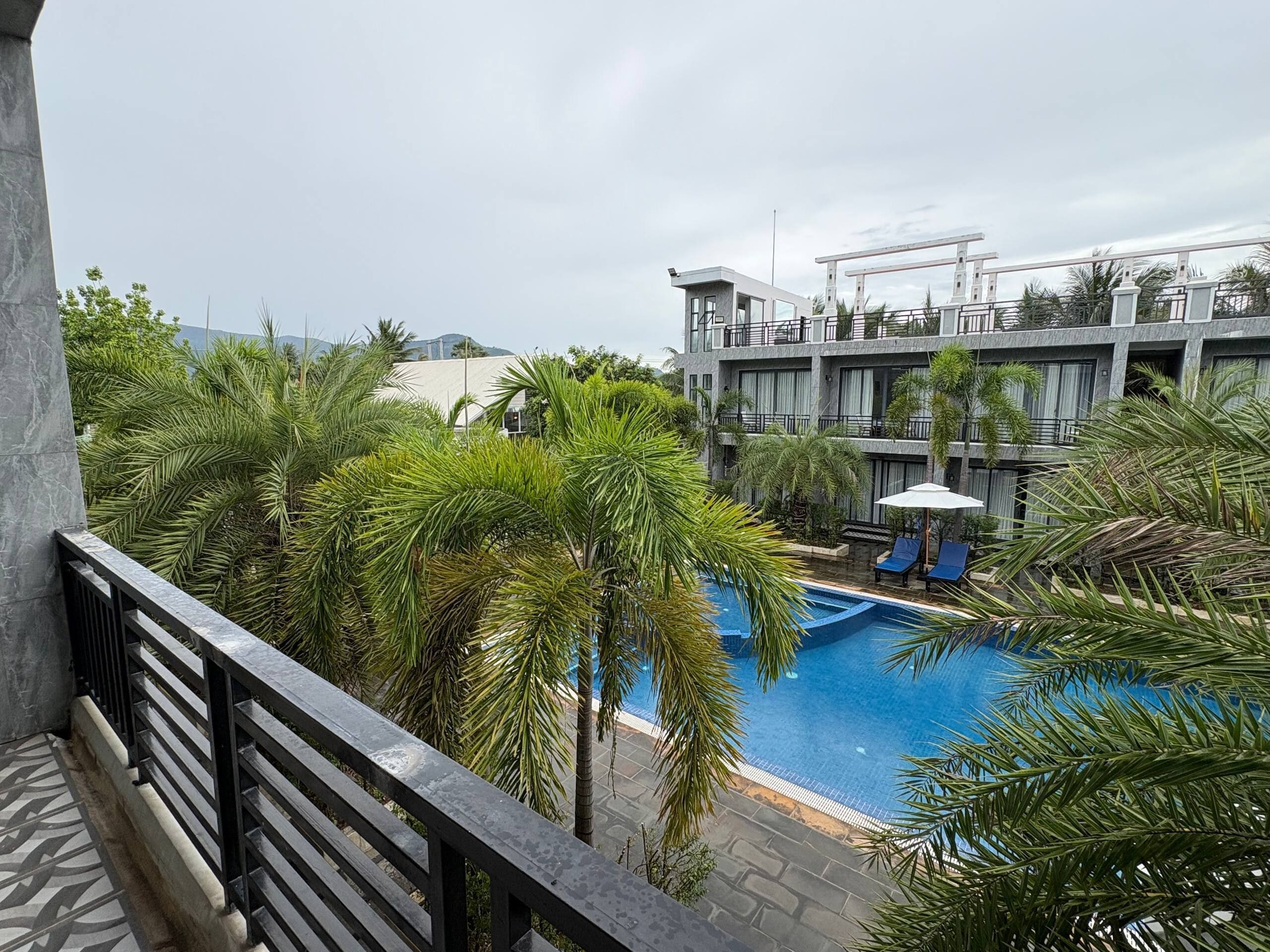 Uma área de piscina com vista para um edifício alto, rodeada por palmeiras.