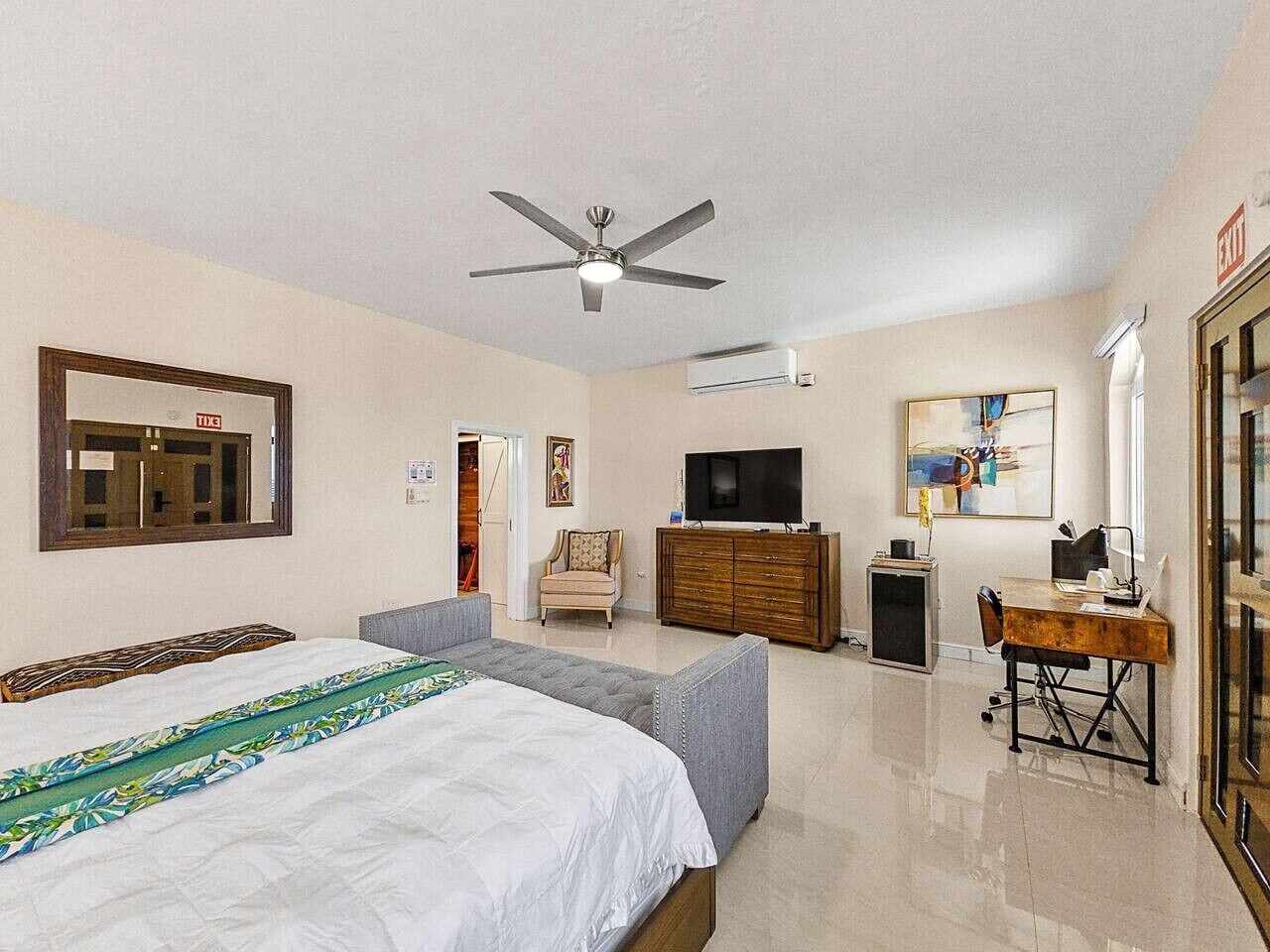 Quarto de hotel com cama, escrivaninha, cadeira, televisão e ar condicionado.