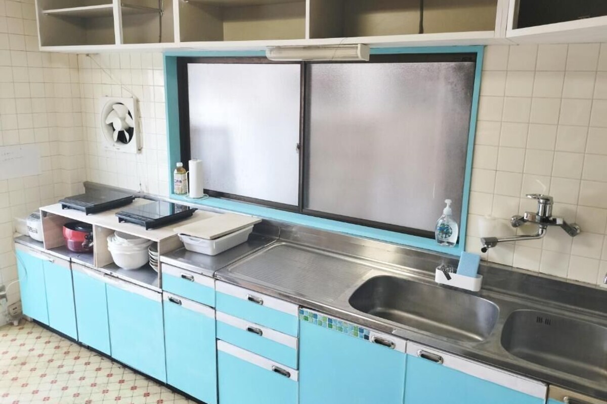 Cozinha com pia de aço inoxidável, armários azuis e backsplash de azulejos brancos.