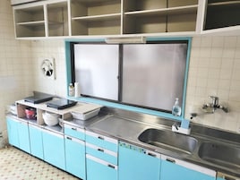 Cozinha com pia de aço inoxidável, armários azuis e backsplash de azulejos brancos.