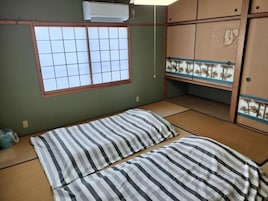 Quarto com piso de tatame, futon, divisória de papel shoji e armário tradicional japonês.