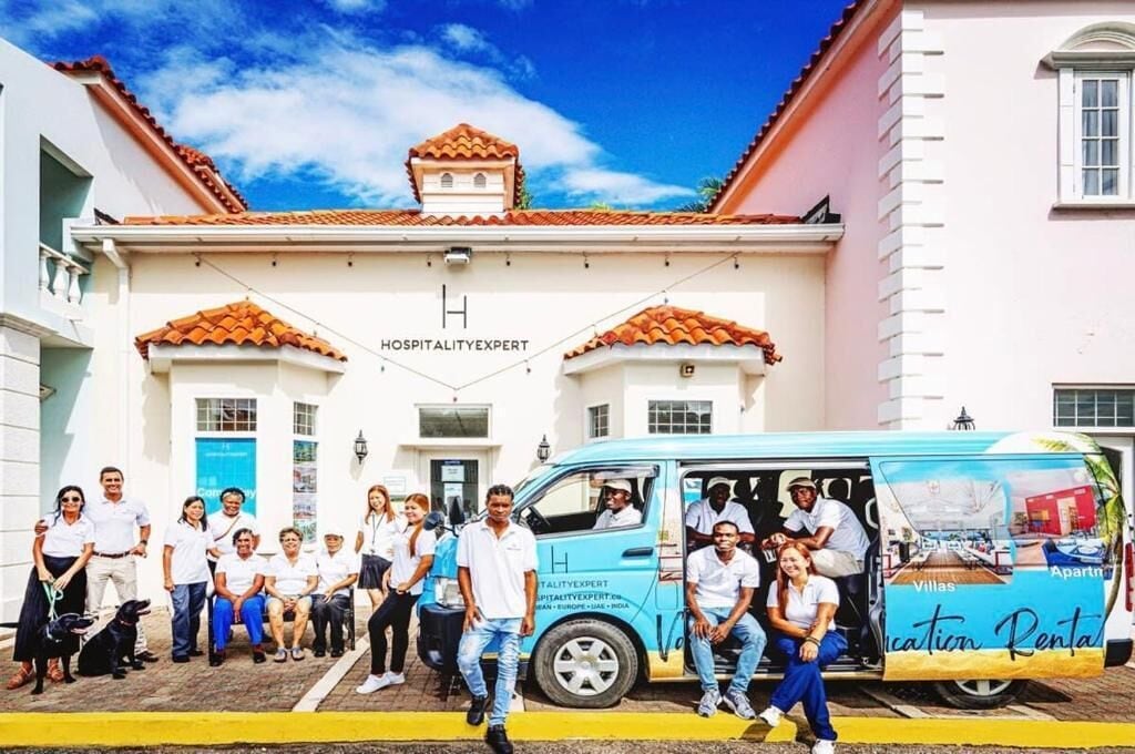 Um grupo de pessoas em frente a um edifício com uma placa que diz 'HOSPITALITY EXPERT'.