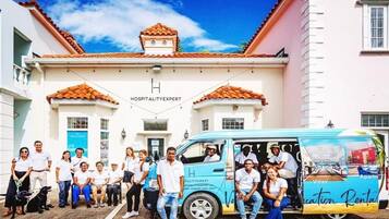 Um grupo de pessoas em frente a um edifício com uma placa que diz 'HOSPITALITY EXPERT'.