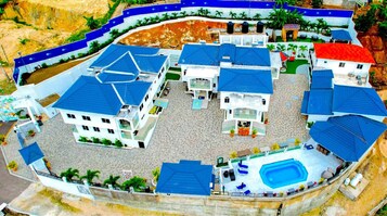 Um resort com vários edifícios, uma piscina central e uma área de praia arenosa.
