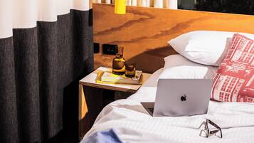 Cama bem arrumada com um laptop, um par de óculos e um livro intitulado 'It's a Mood' sobre a mesa de cabeceira.