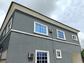 Um edifício de dois andares com fachada cinza, detalhes brancos e várias janelas.