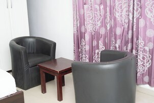 Um quarto com poltrona de couro escura, uma mesa de madeira e um banquinho combinando.