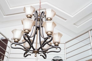 Um candelabro com vários braços e luminárias, pendurado em um teto com padrão geométrico.