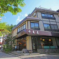 Um edifício com restaurante no andar térreo, com grandes janelas e fachada de pedra.