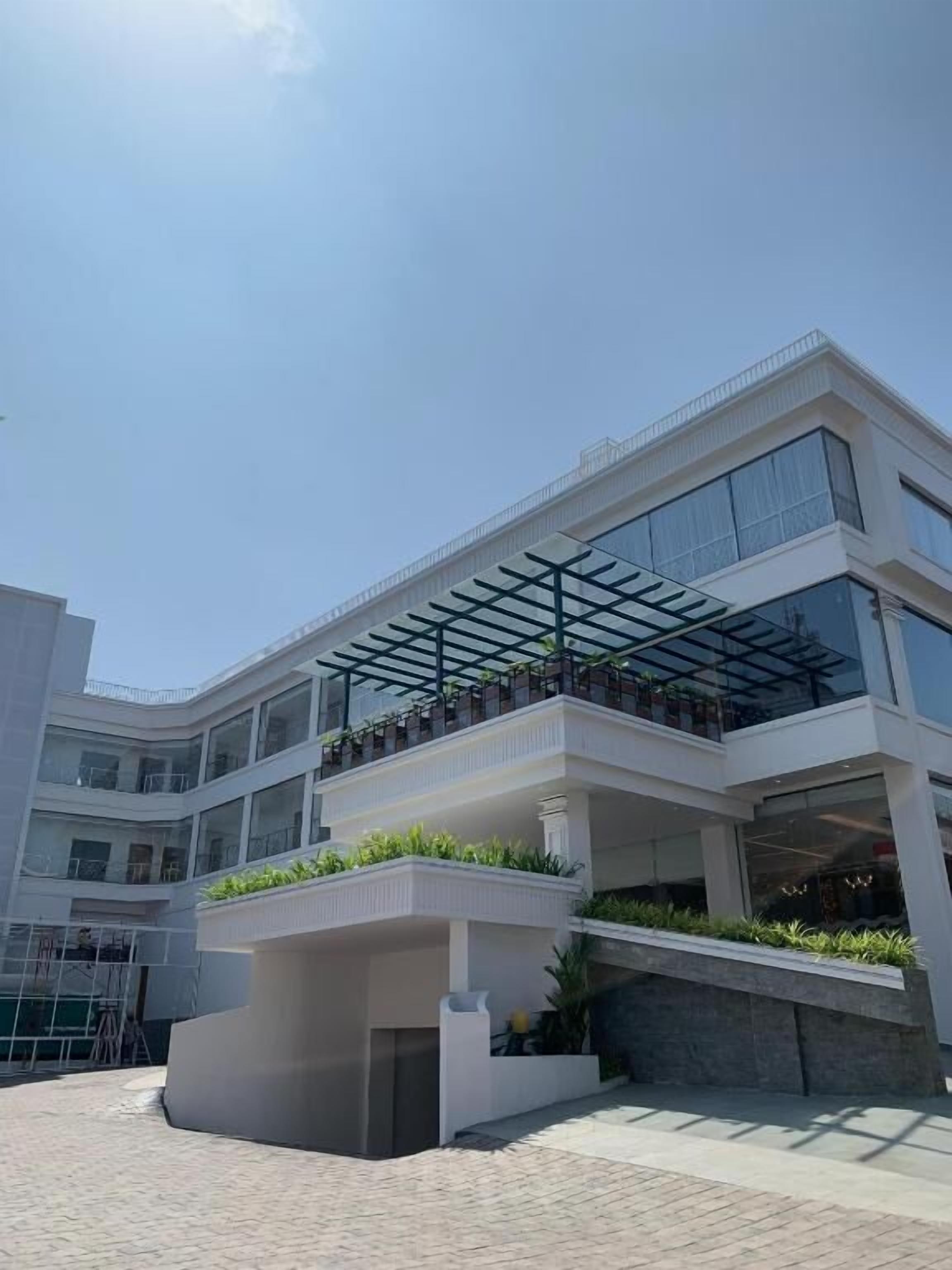 Um edifício moderno de vários andares com fachada de vidro, áreas de estar ao ar livre e um terraço ajardinado.