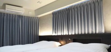 Quarto de hotel com cama, cortinas, ar condicionado e cabeceira.
