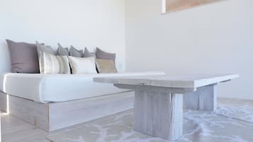 Quarto minimalista com uma cama, uma mesa de centro de madeira e um tapete estampado.