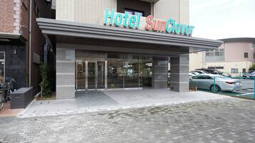 Entrada de hotel com design moderno, apresentando uma placa chamativa com a inscrição 'Hotel Sunflower'.