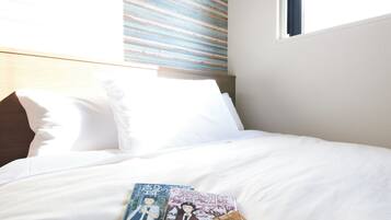 Cama bem arrumada com lençóis brancos e almofada, janela com vista do céu e parede listrada atrás da cama.
