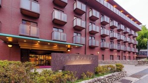Um hotel de vários andares com fachada vermelha, varandas e entrada de pedra.