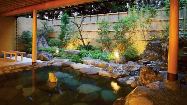 Um jardim japonês tradicional com um lago de carpas, pedras e um banco de madeira.