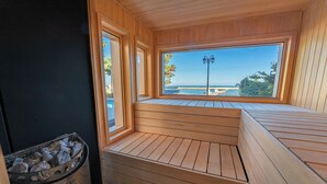 Uma sala de sauna com bancos de madeira e uma janela grande com vista para o mar.