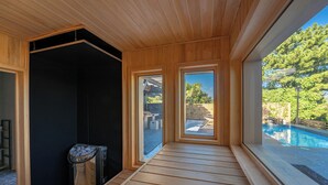 Interior moderno com soalho de madeira, grandes janelas e vista para uma piscina exterior.