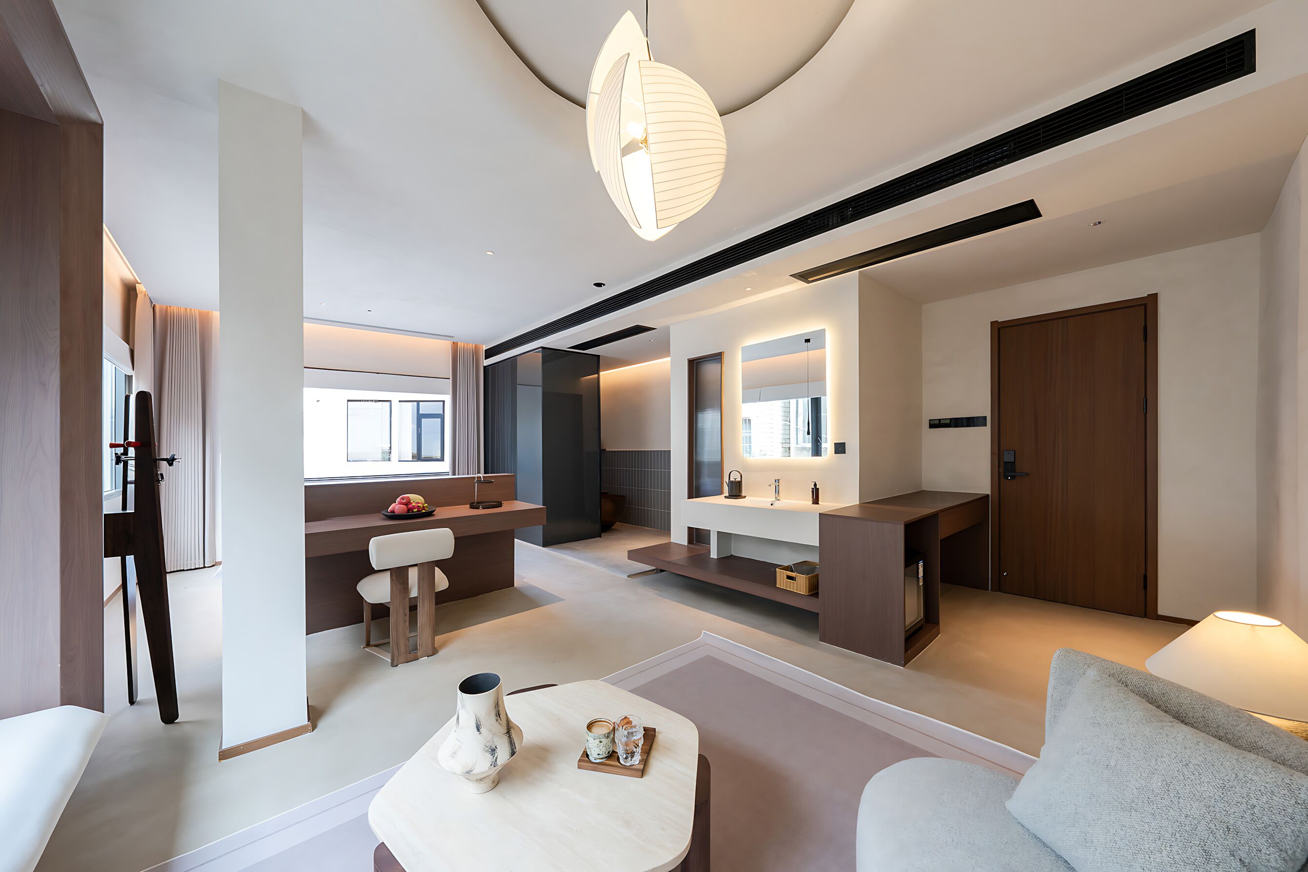 Quarto de hotel moderno com escrivaninha, área de estar e um espelho grande.