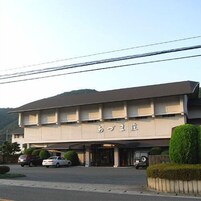 Um edifício com uma placa indicando 'あつまま荘' e um estacionamento com carros.