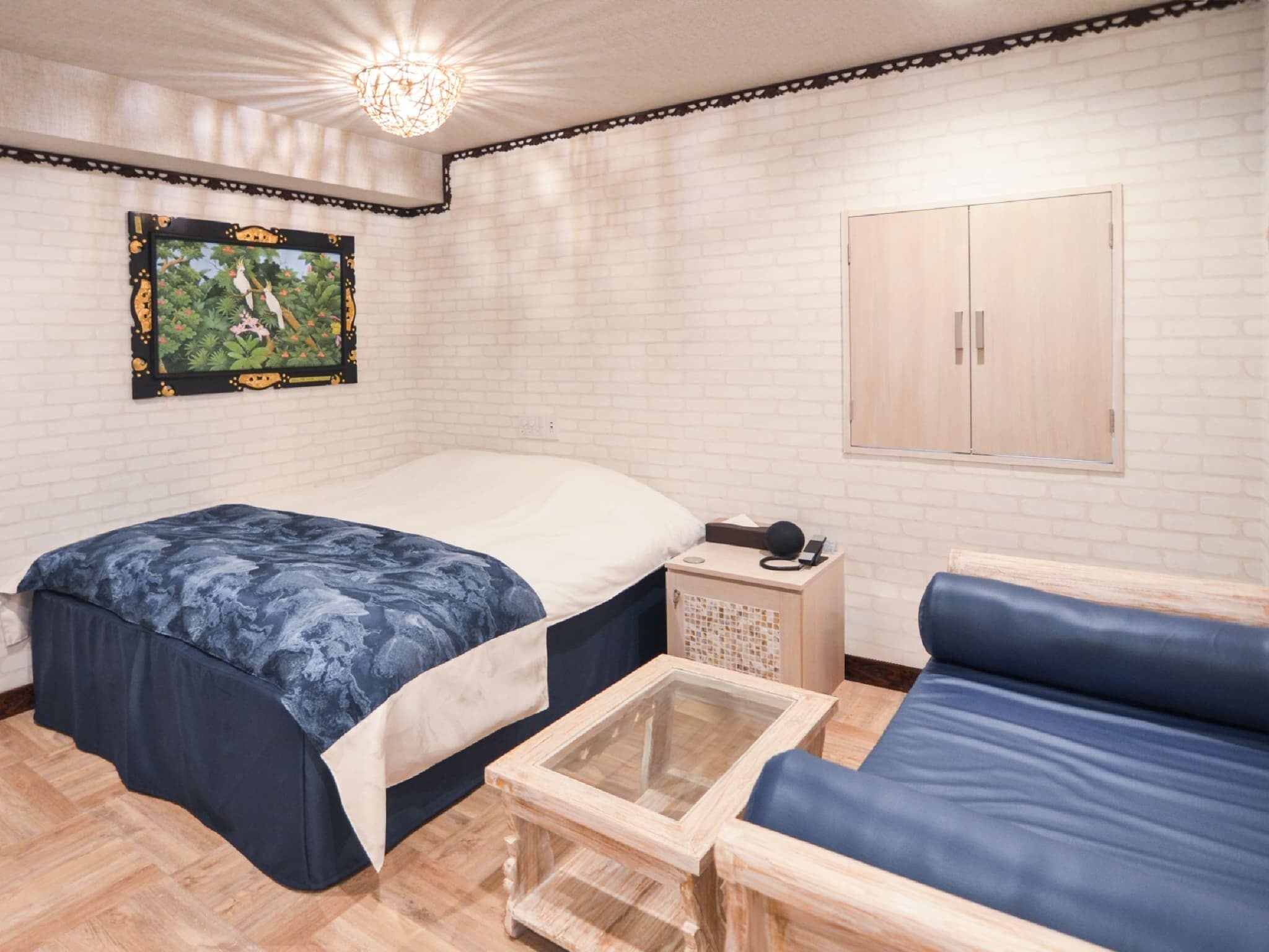 Um quarto com uma cama, um sofá, uma mesinha, um armário e um quadro na parede.