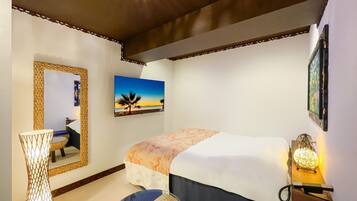 Quarto de hotel com cama, um quadro, um espelho e uma luminária.