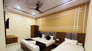 Quarto de hotel com duas camas, um ventilador de teto, iluminação embutida e uma cabeceira de madeira.