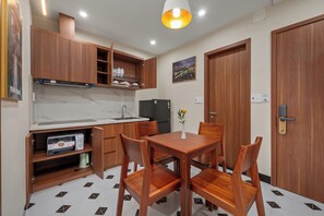 Uma cozinha compacta com armários de madeira, micro-ondas embutido e uma mesa de jantar com cadeiras.