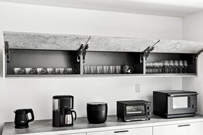Uma cozinha equipada com cafeteira, chaleira, micro-ondas e torradeira.