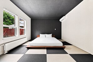 Quarto moderno com cama, radiador e janela com vista para o verde.