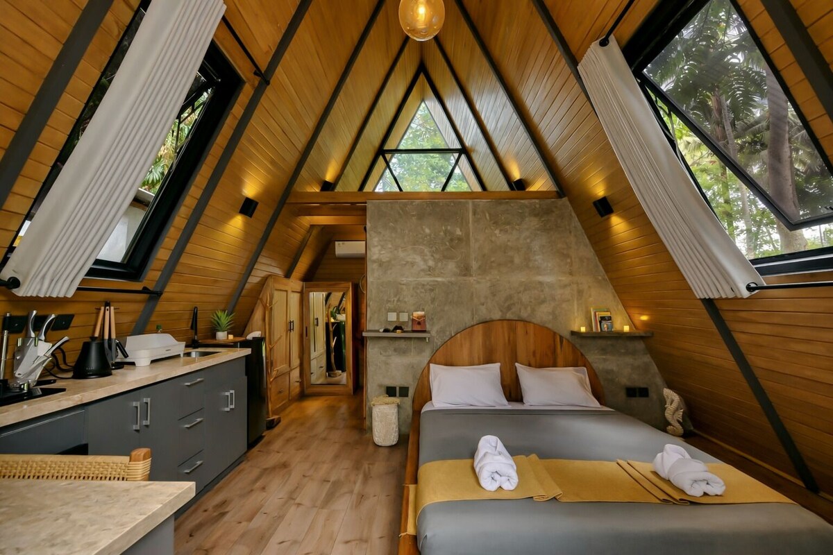Um quarto com uma cama, teto de madeira, parede de pedra e uma janela.